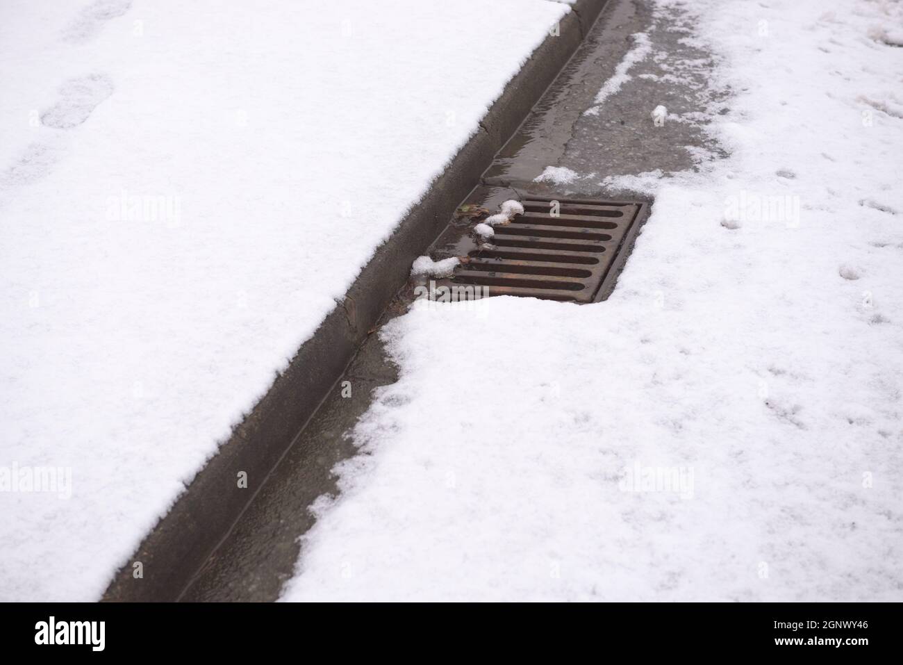 2 - Road covered in heavy snow with only the curbside drain showing. As ...