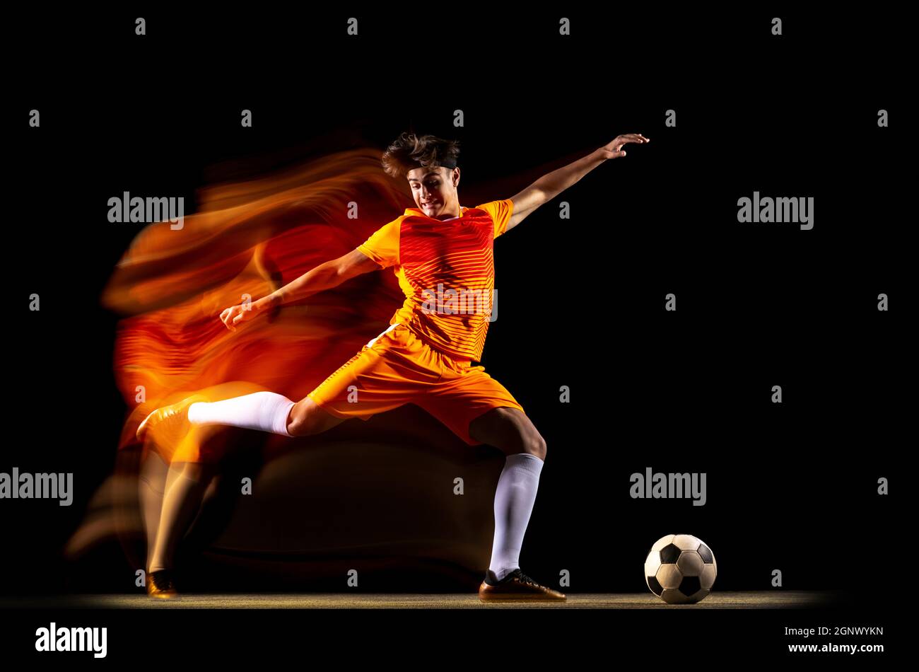 Young professional football soccer player training isolated over black ...