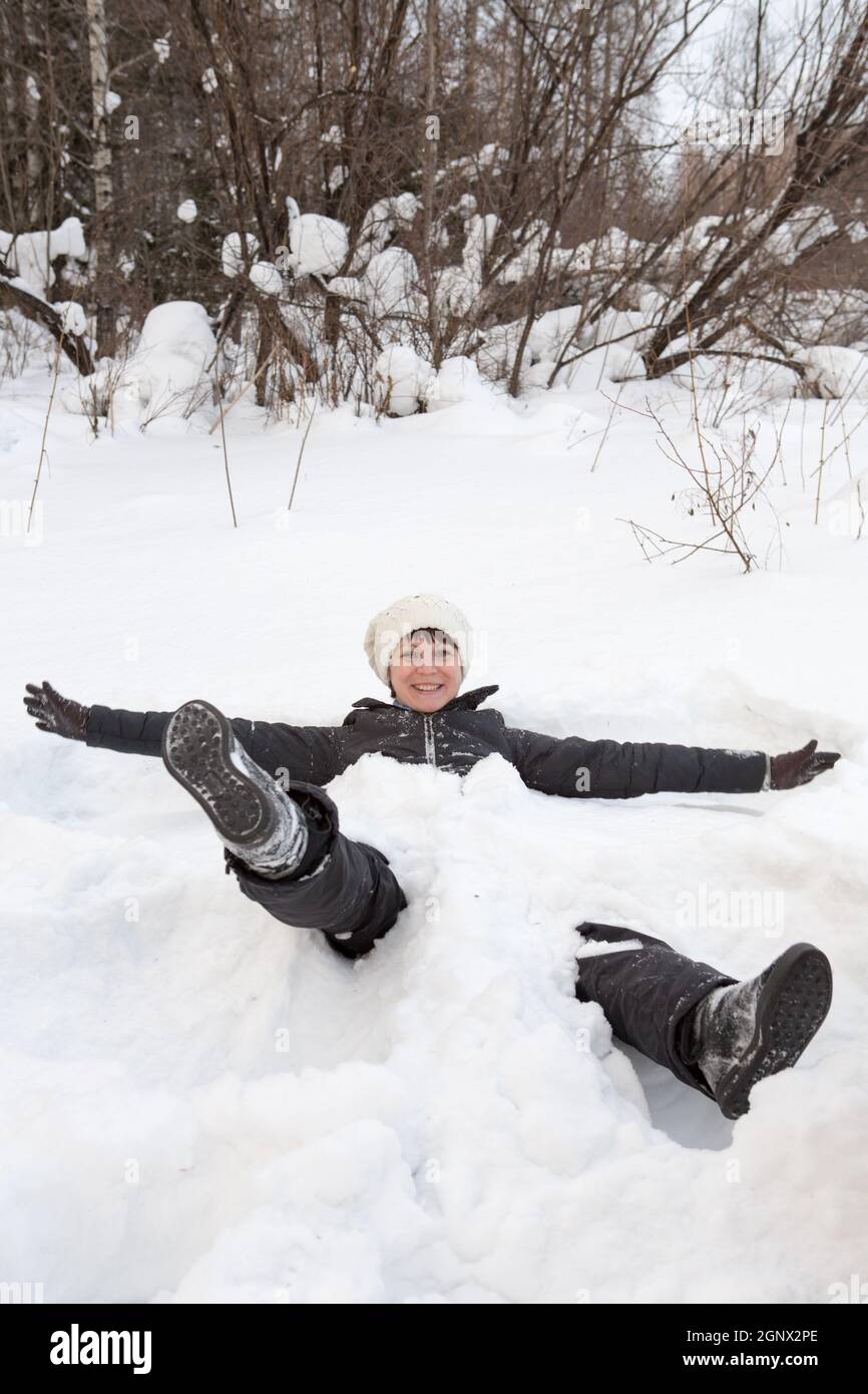 Side view of a beautiful young woman laying down on a frozen snow lake ...