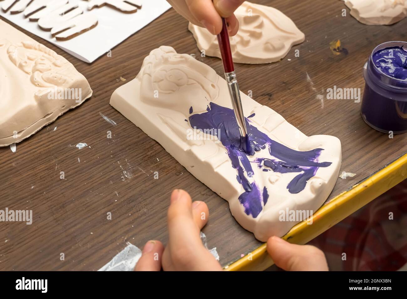 The child draws with a brush, gouache and paints on a plaster figure ...