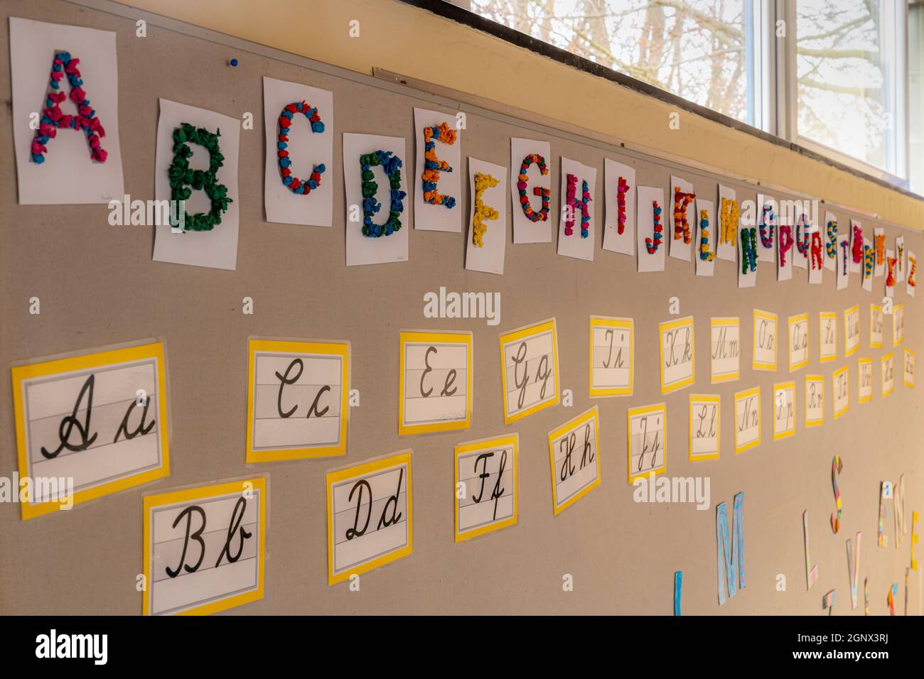 Colored letters, alphabet in block and cursive on the wall of a primary ...