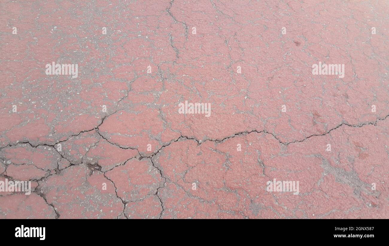 Red colored damaged road or paved pathway with crackes of different ...