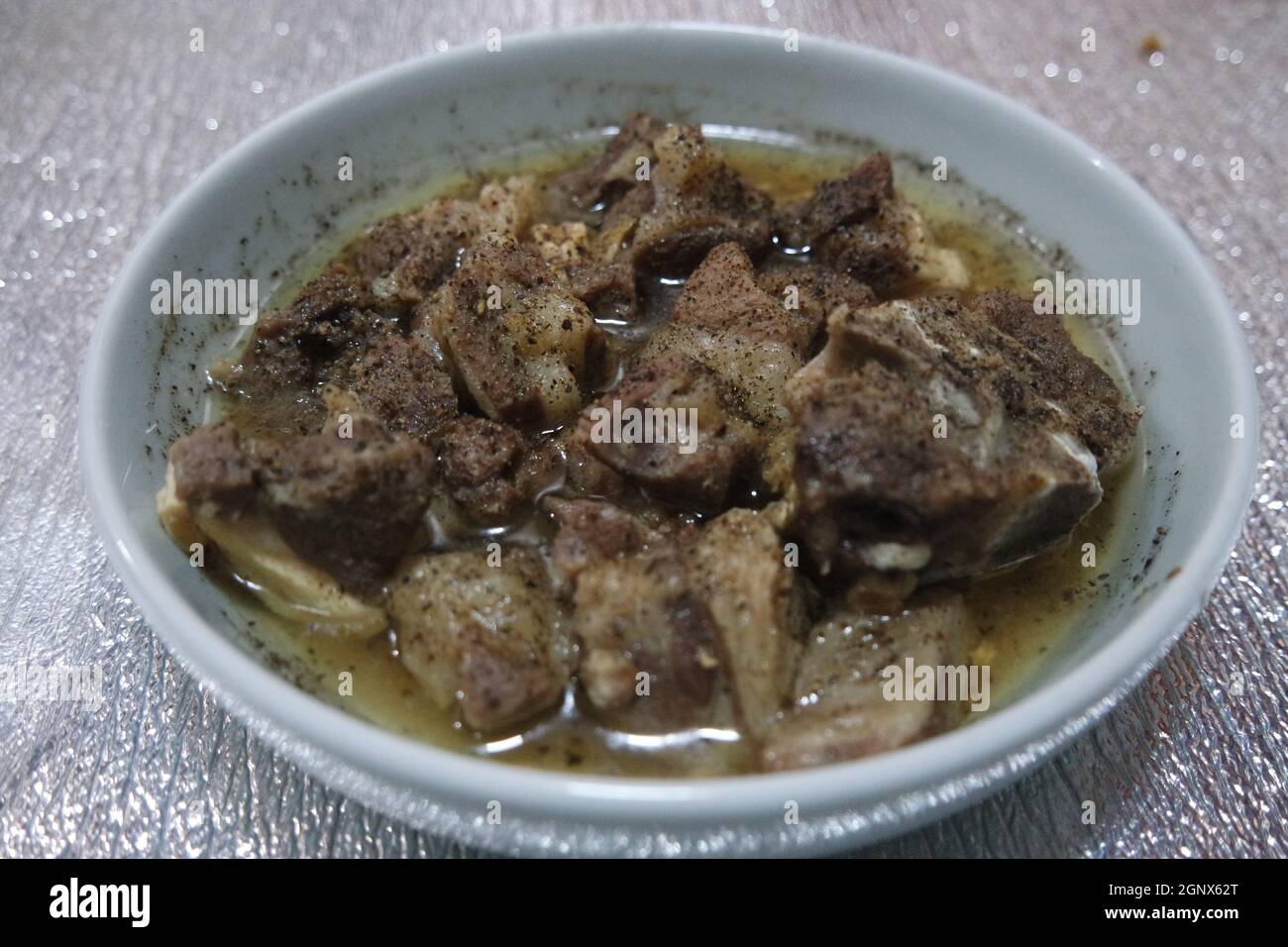 Top view of siri paaye or paya dish garnished with diced ginger, long ...