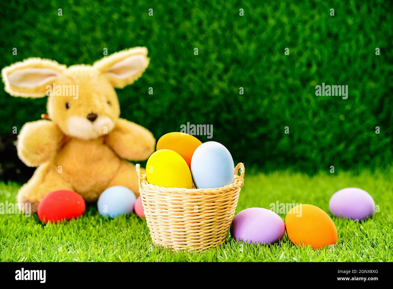 Easter bunny toy and Easter eggs in basket on green grass Stock Photo ...