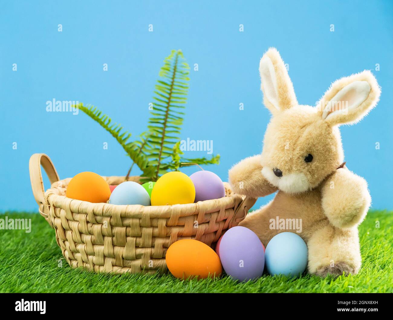 Easter bunny toy and Easter eggs in basket on green grass Stock Photo ...