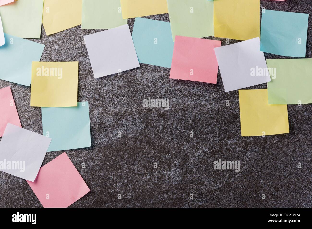 Many blank multicolored paper stick note list on concrete wall ...