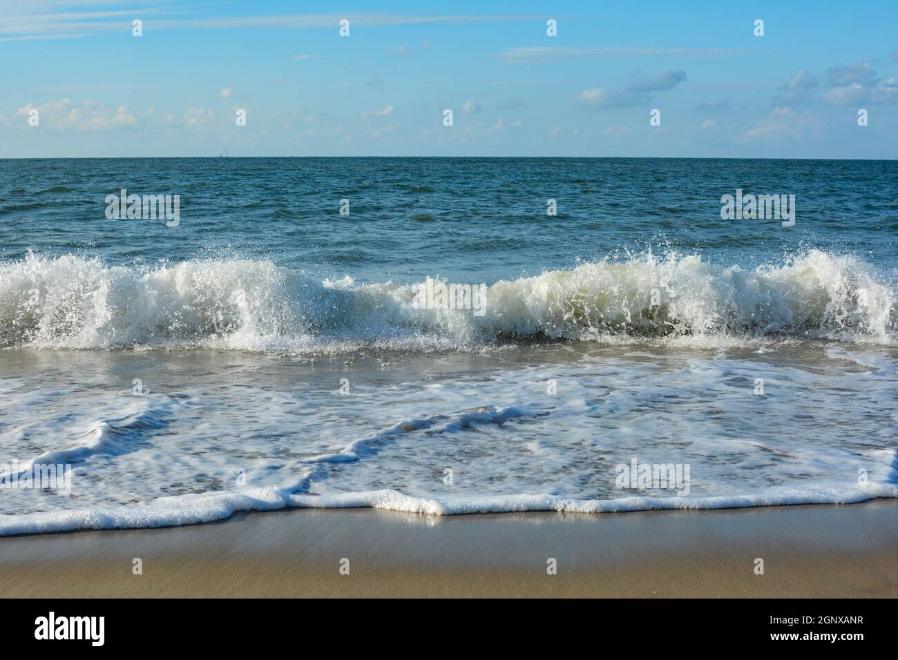 Waves on sand beach with blue sky Stock Photo - Alamy