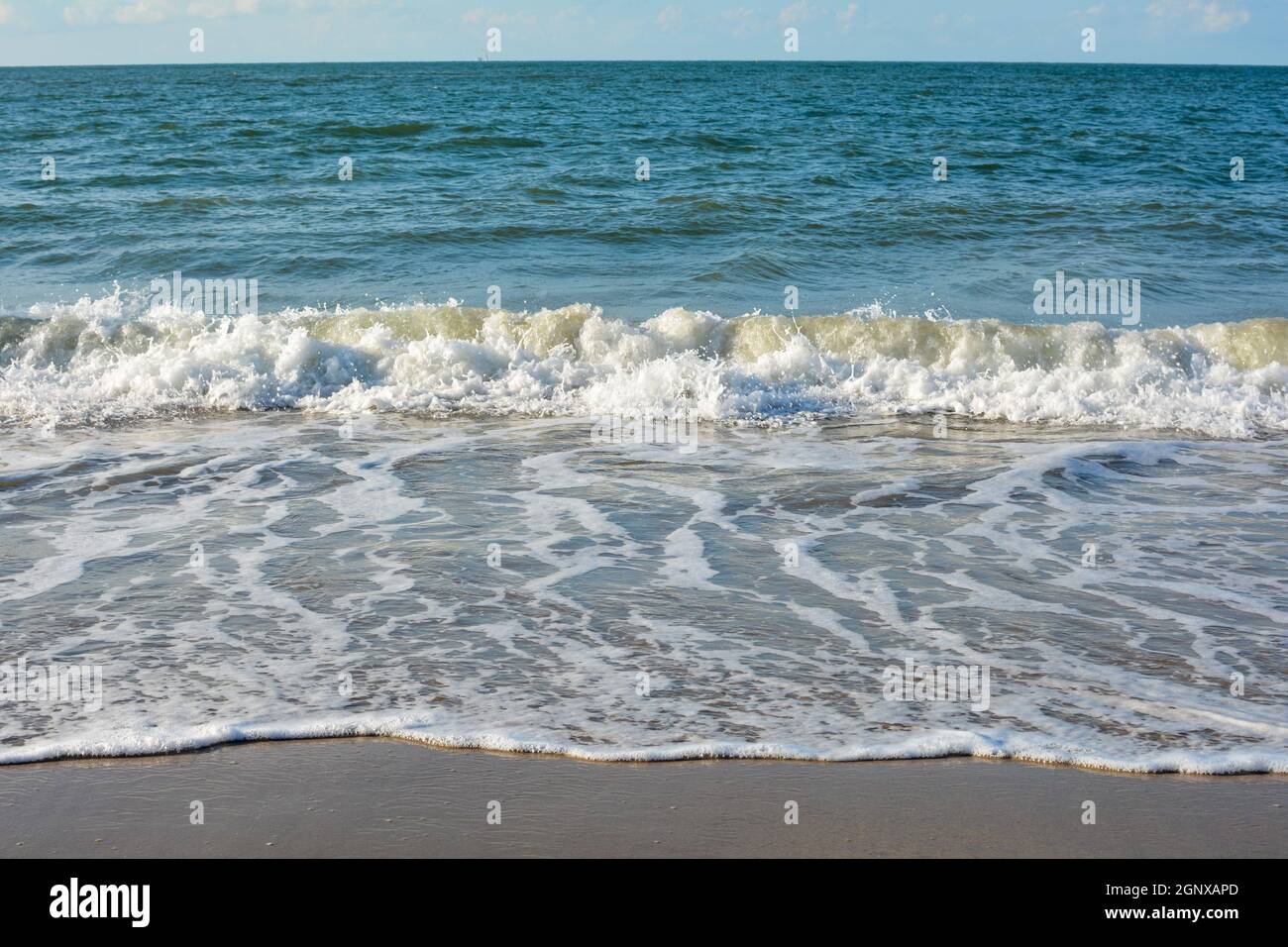 Waves on sand beach with blue sky Stock Photo - Alamy