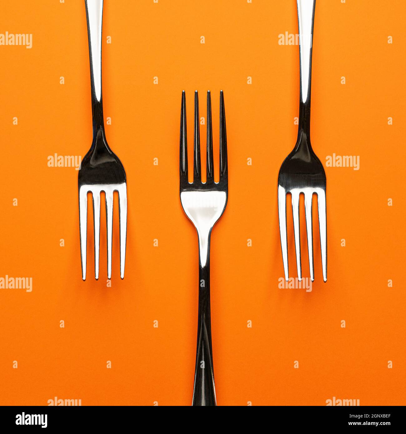 three forks arranged on an orange surface Stock Photo - Alamy