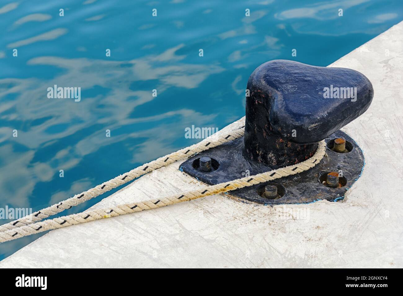 Black old iron bollard on concrete marine dock for boat Stock Photo - Alamy