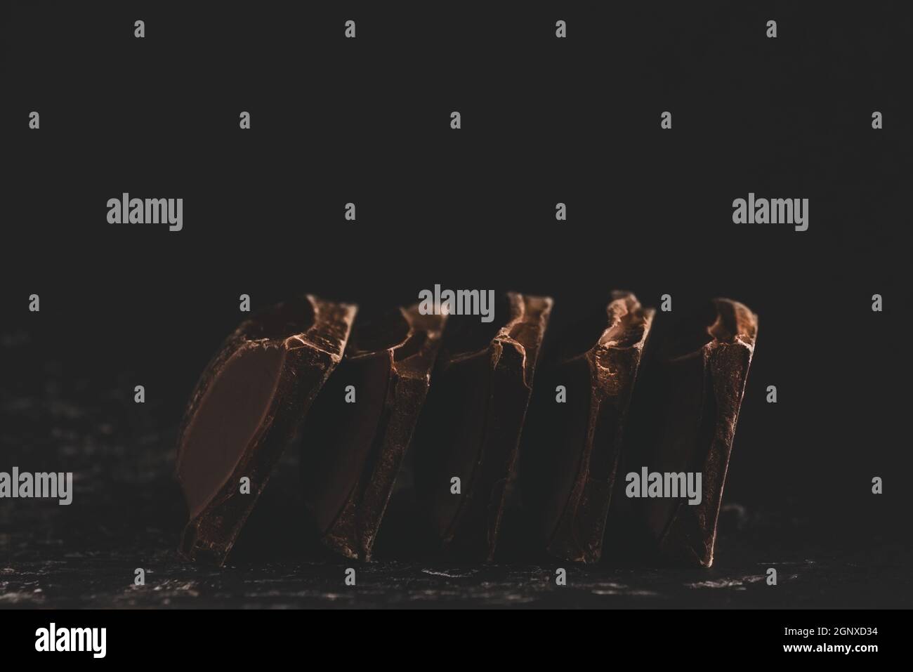 Closeup of broken dark chocolate blocks stack on black background with ...