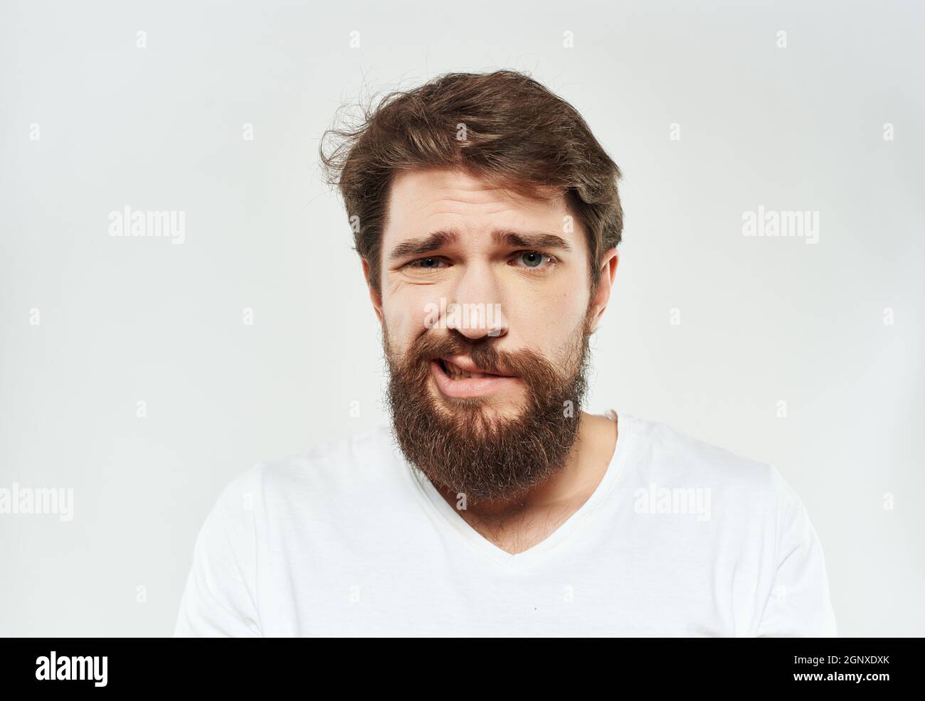 bearded man in a white t-shirt irritated facial expression Studio Stock ...