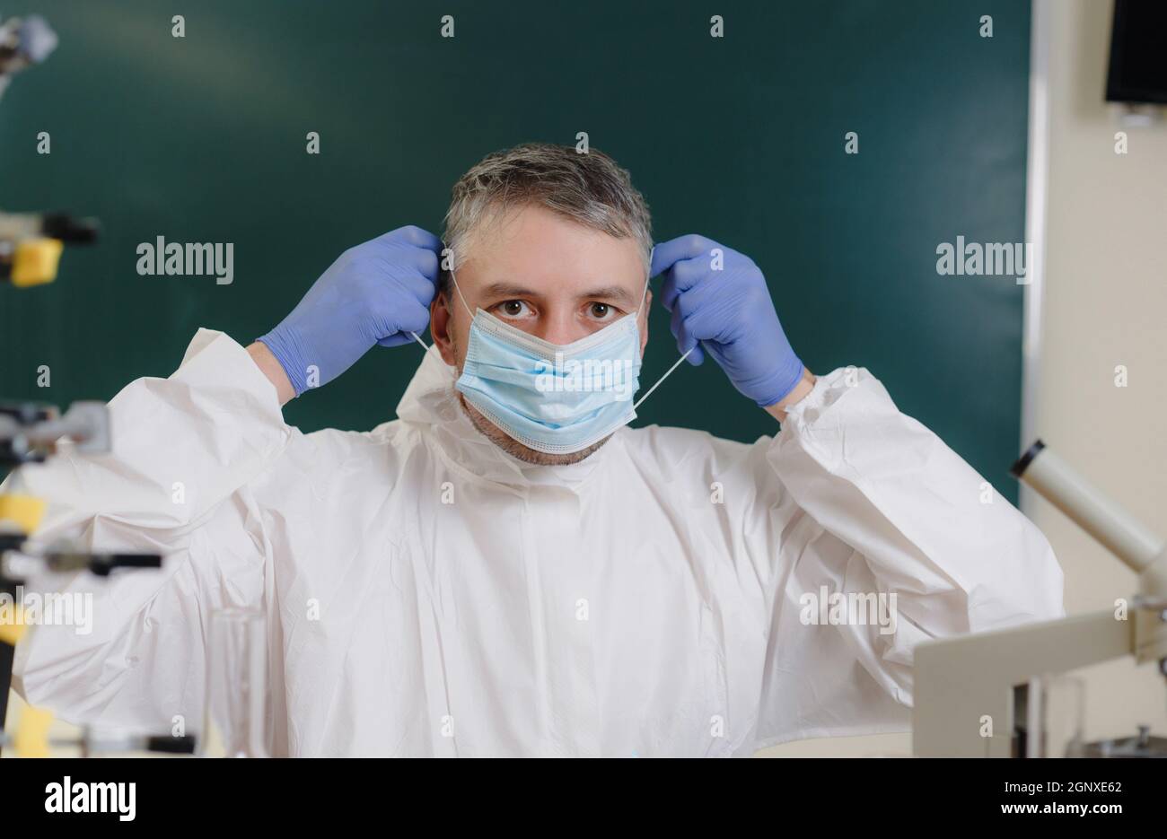 A young scientist in a chemical laboratory puts a protective mask on ...