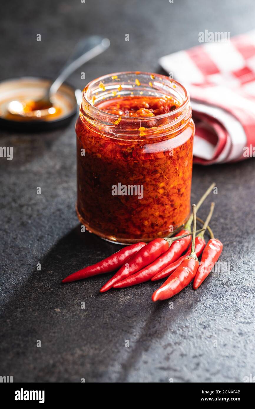 Red hot chili paste and chili pepper in jar on black table Stock Photo ...