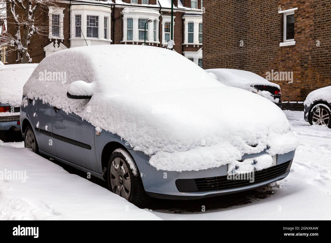 Street winter cityscape with snow covered frozen cars after a blizzard ...
