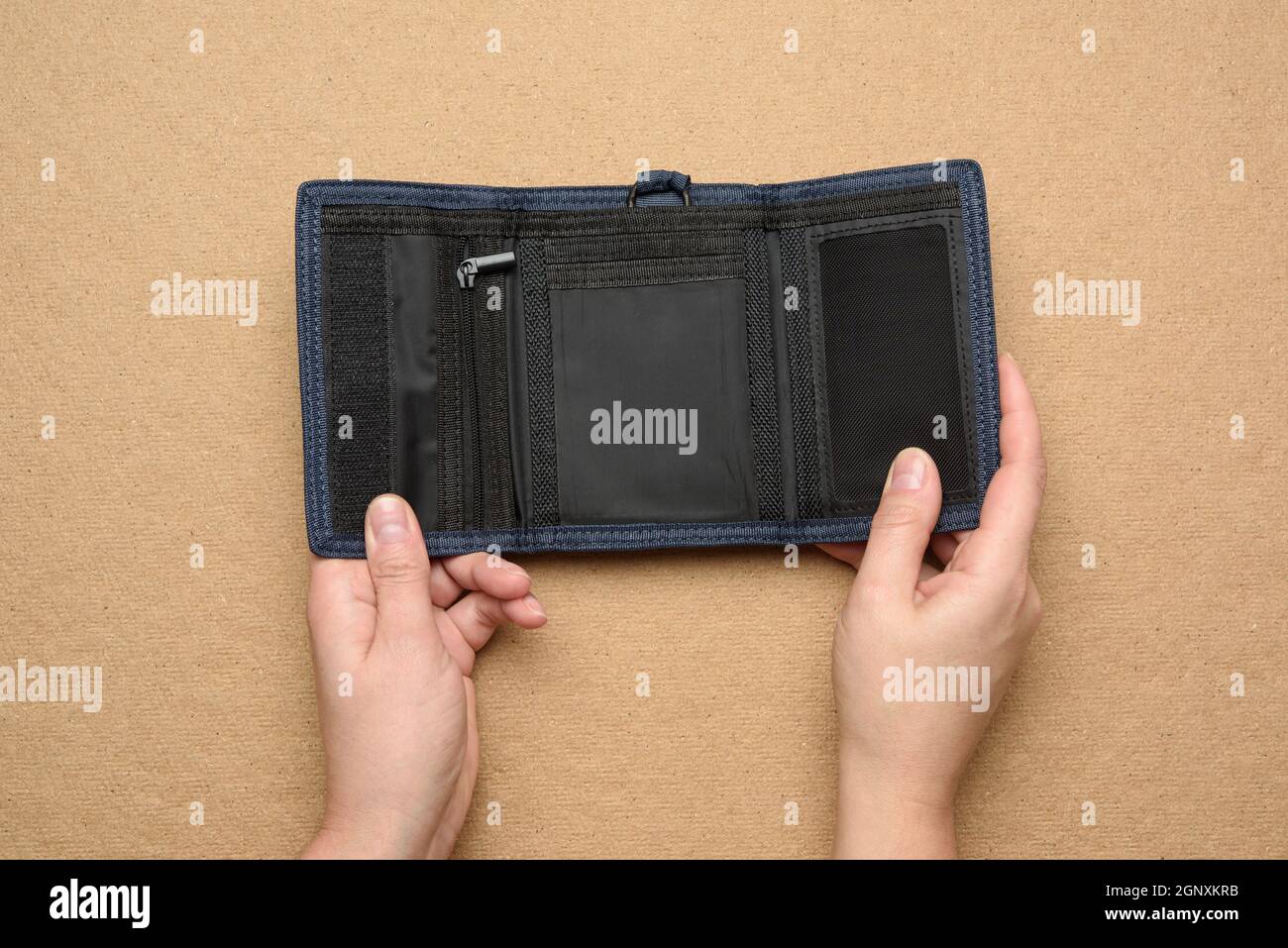 female hands hold open empty blue textile wallet on brown background ...