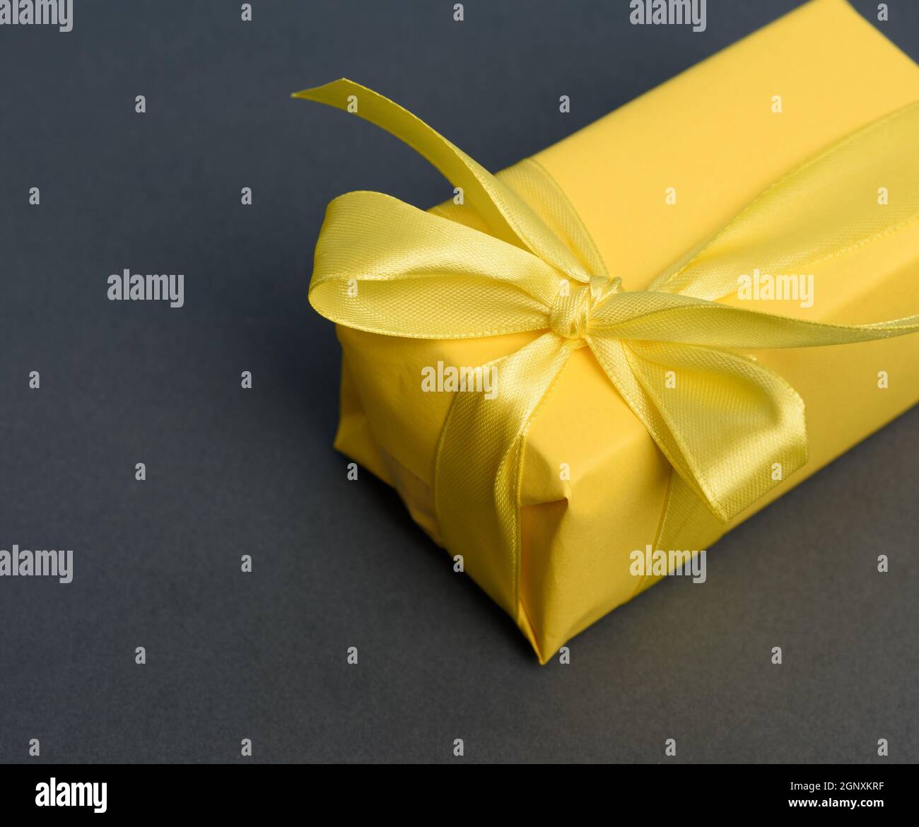 rectangular box with a gift wrapped in yellow paper and tied with a ...