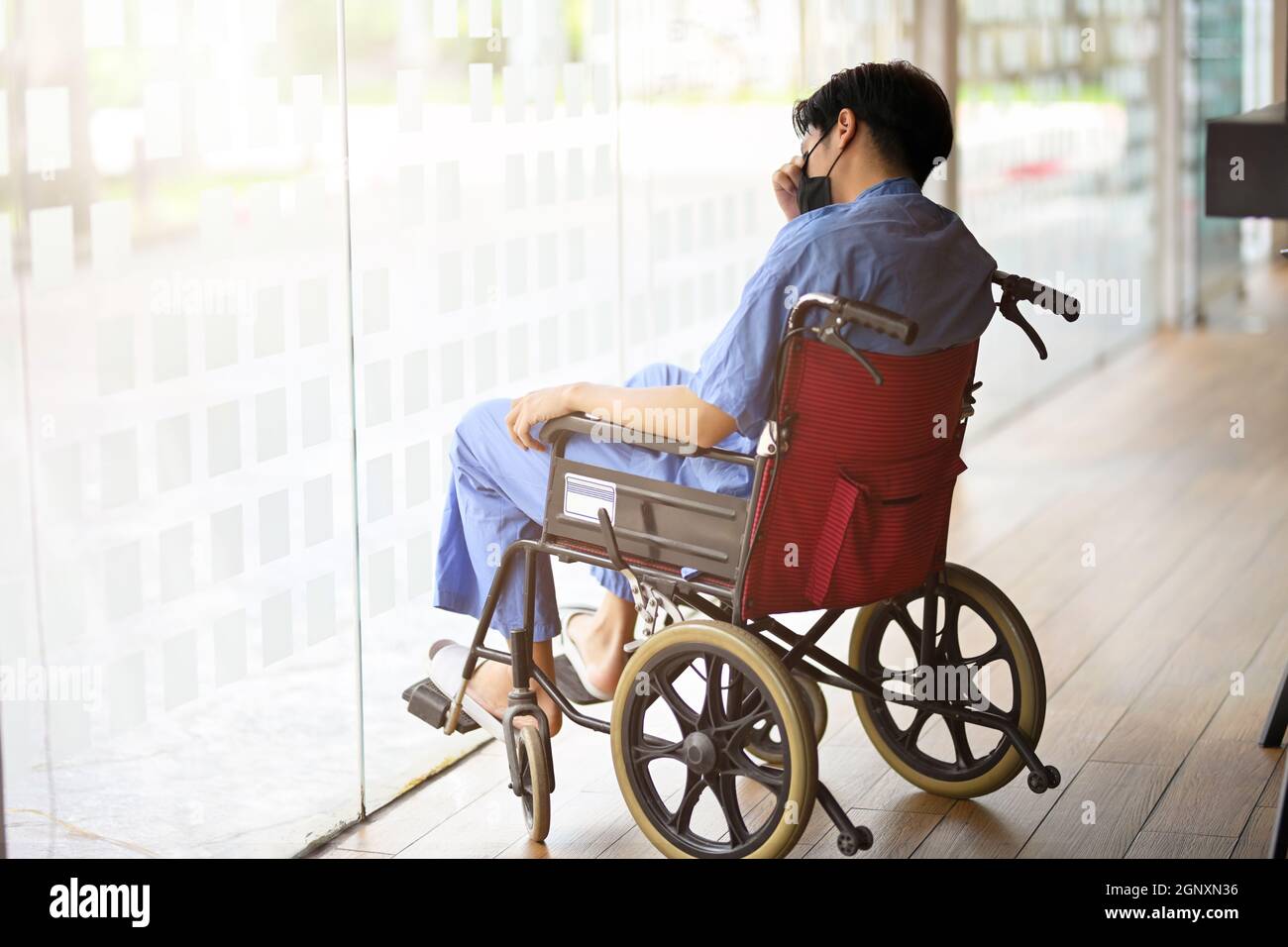 Depressed handicapped male patient in wheelchair looking out through ...