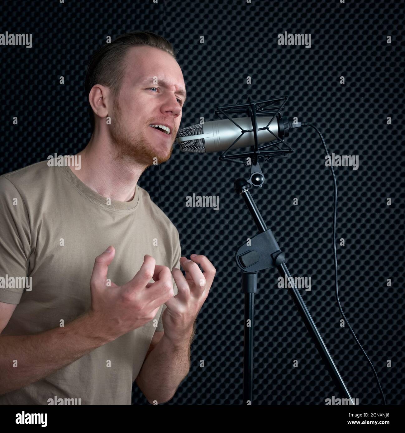 Young caucasian man singing in front of black soundproofing walls ...