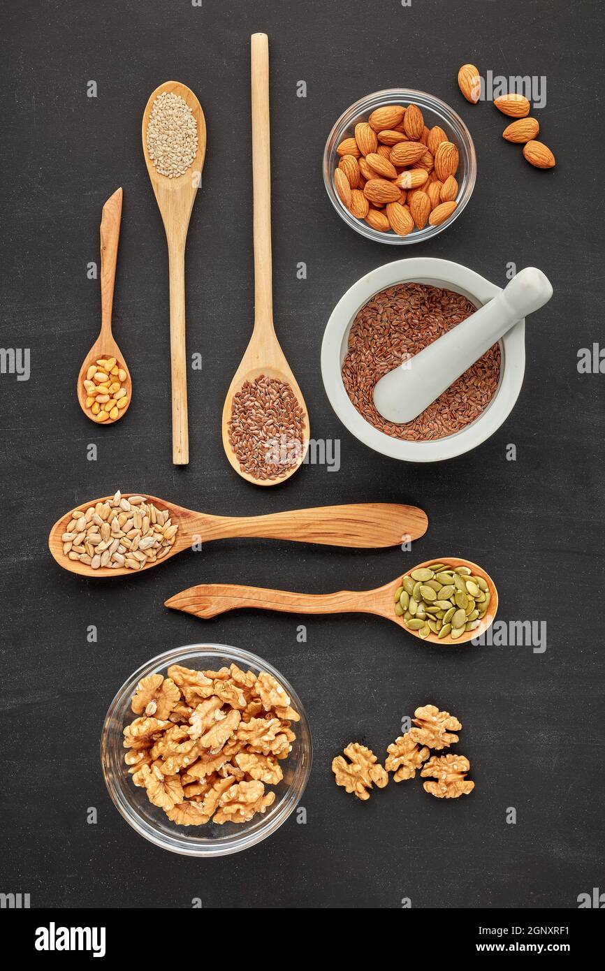 Various varieties of nuts and seeds lying in wooden spoones and bowls ...