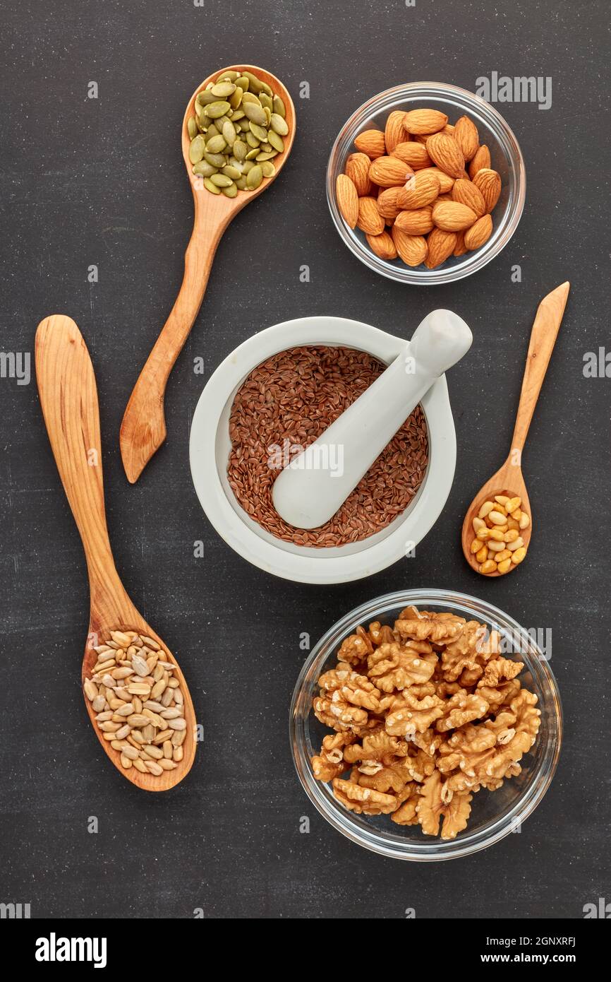 Various varieties of nuts and seeds lying in wooden spoones and bowls ...