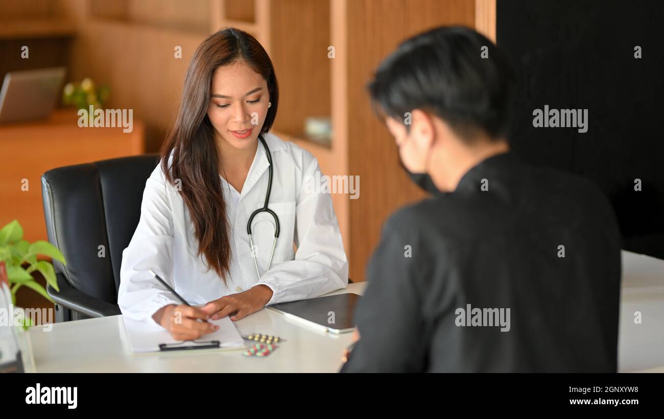 Asian female doctor writing down patient's symptoms and drugs ...