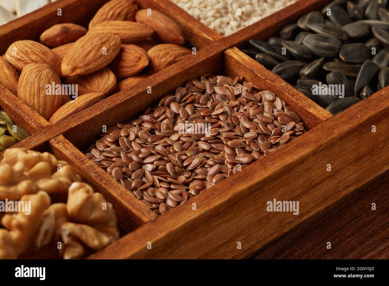 Various varieties of nuts and dried seeds lying in wooden box on brown ...