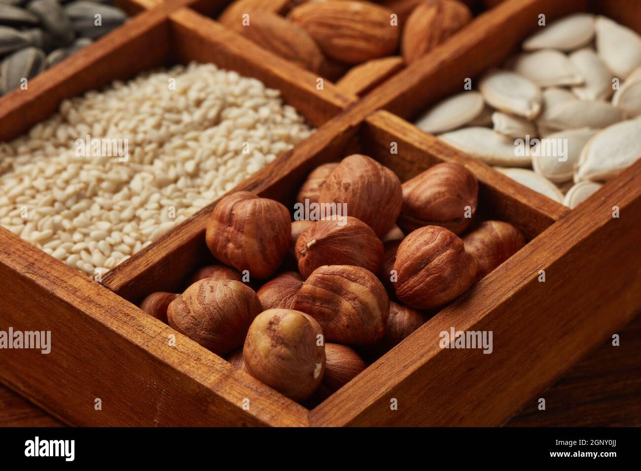 Various varieties of nuts and dried seeds lying in wooden box on brown ...