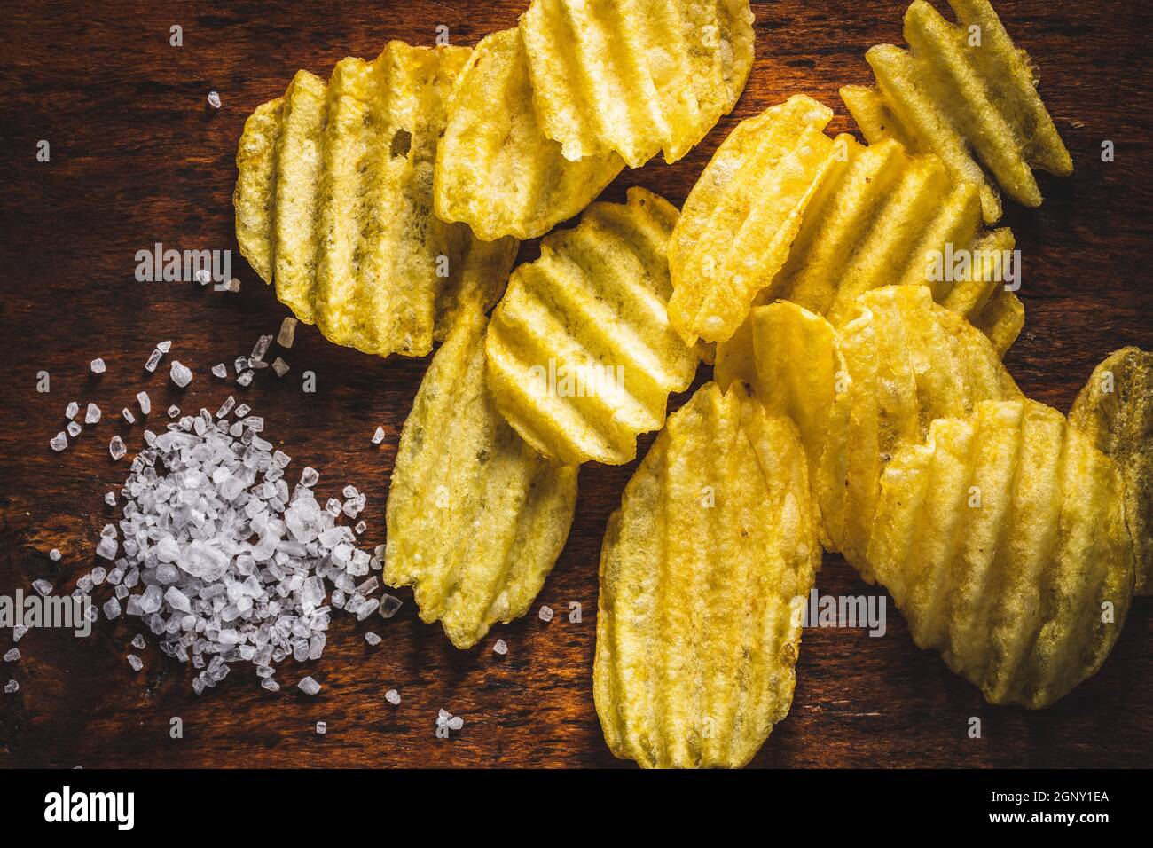Crispy potato chips and salt on wooden table. Top view Stock Photo - Alamy