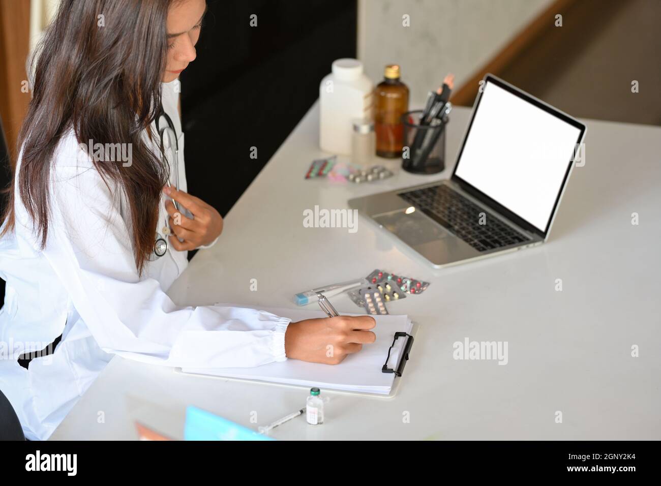 Young female pharmacist taking notes and writing prescriptions on ...