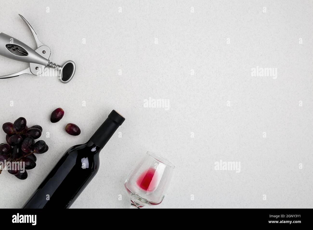 Overhead angled view of a large bottle of red wine, drinking glass on ...