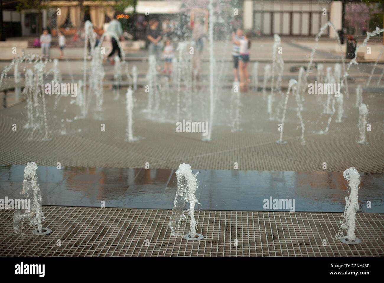 City fountain in the square. Water gushes out from sidewalks. Plane ...