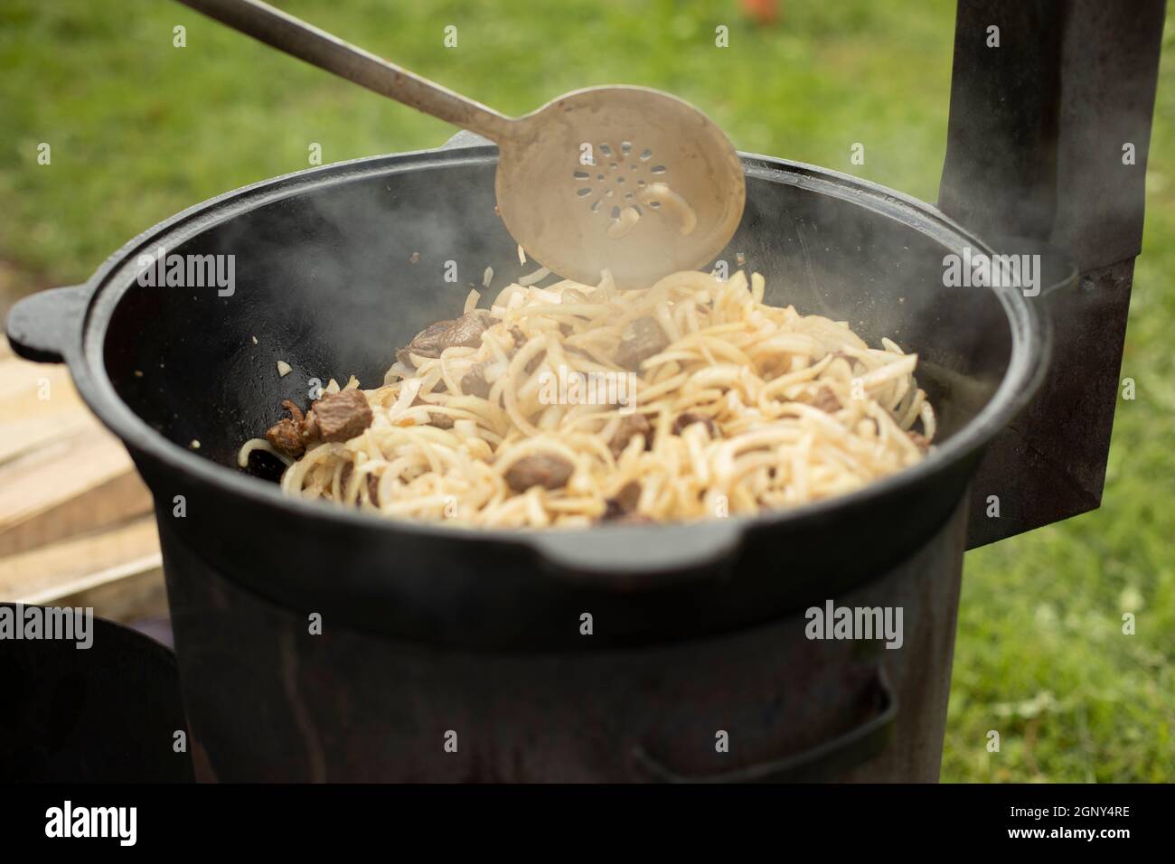 Cooking pilaf. The food is fried in a frying pan. Lunch in nature ...
