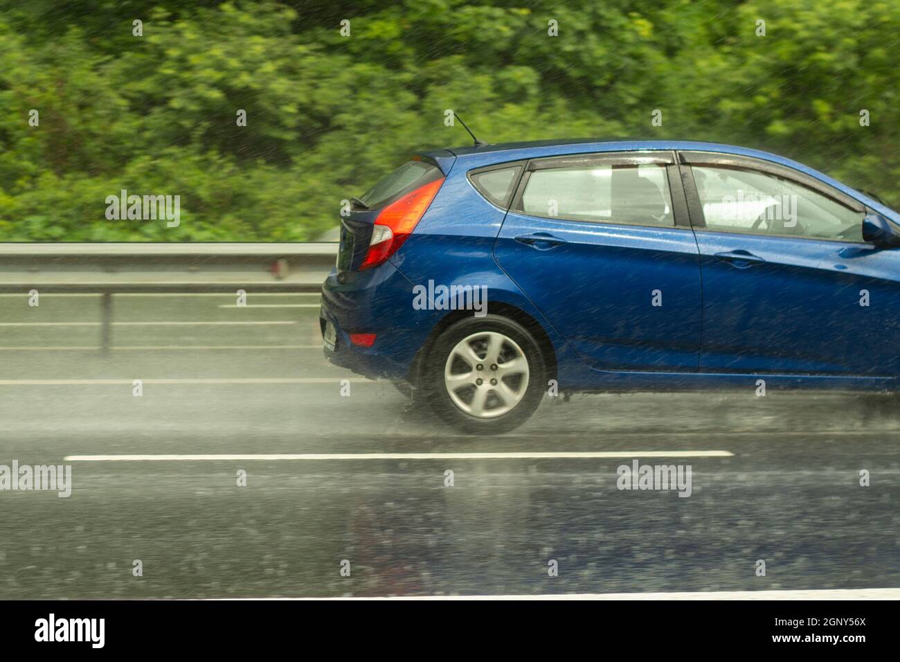 The car is driving on a wet road. Slippery road after rain. Splashes ...