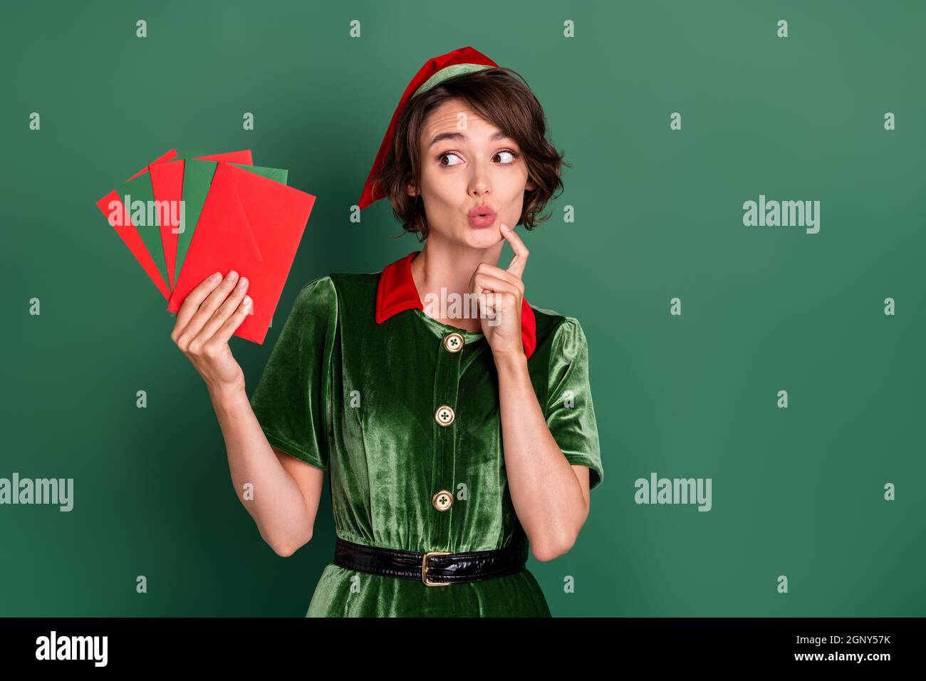 Portrait of attractive amazed girl thinking choosing letter festal ...