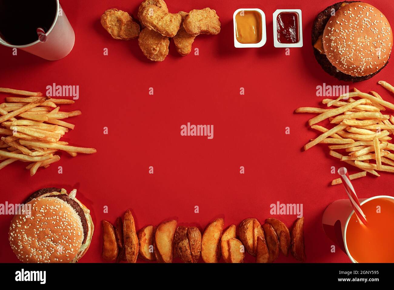 Two hamburgers and french fries, sauces and drinks on red background ...