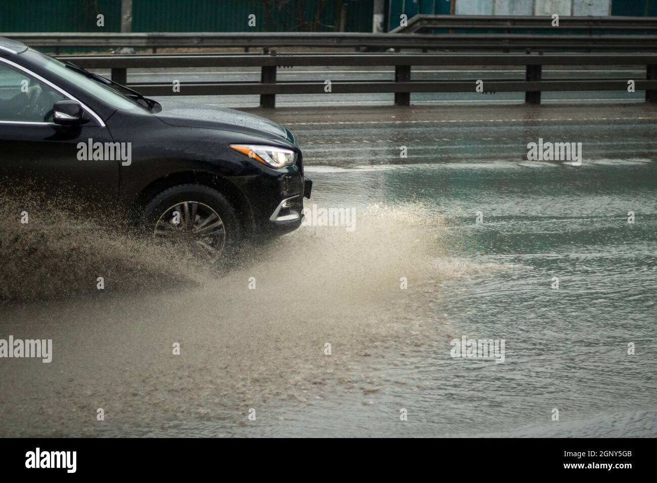 The car is driving through a puddle. Splashes from a puddle on the road ...