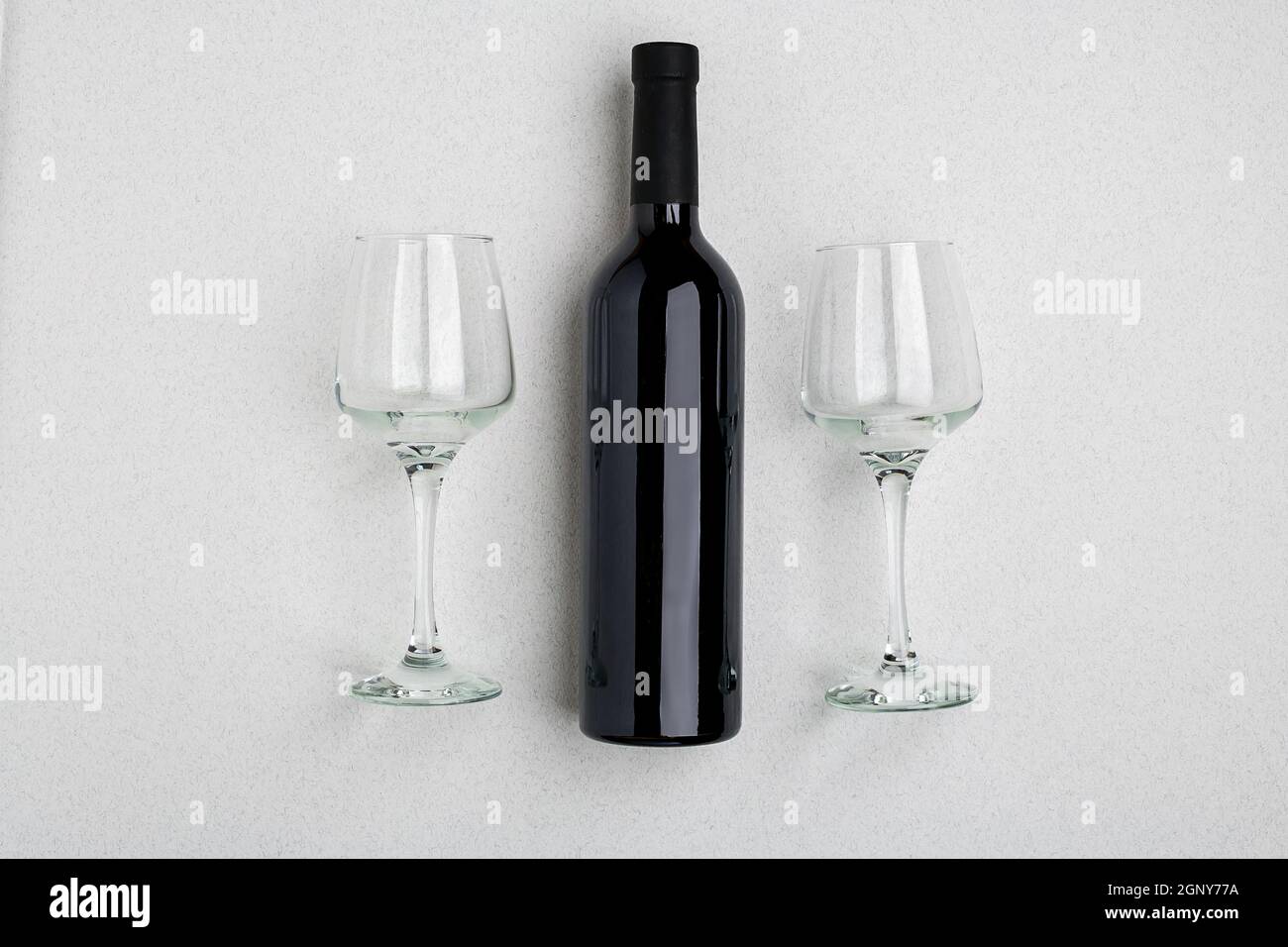Overhead angled view of a large bottle of red wine, drinking glasses on ...