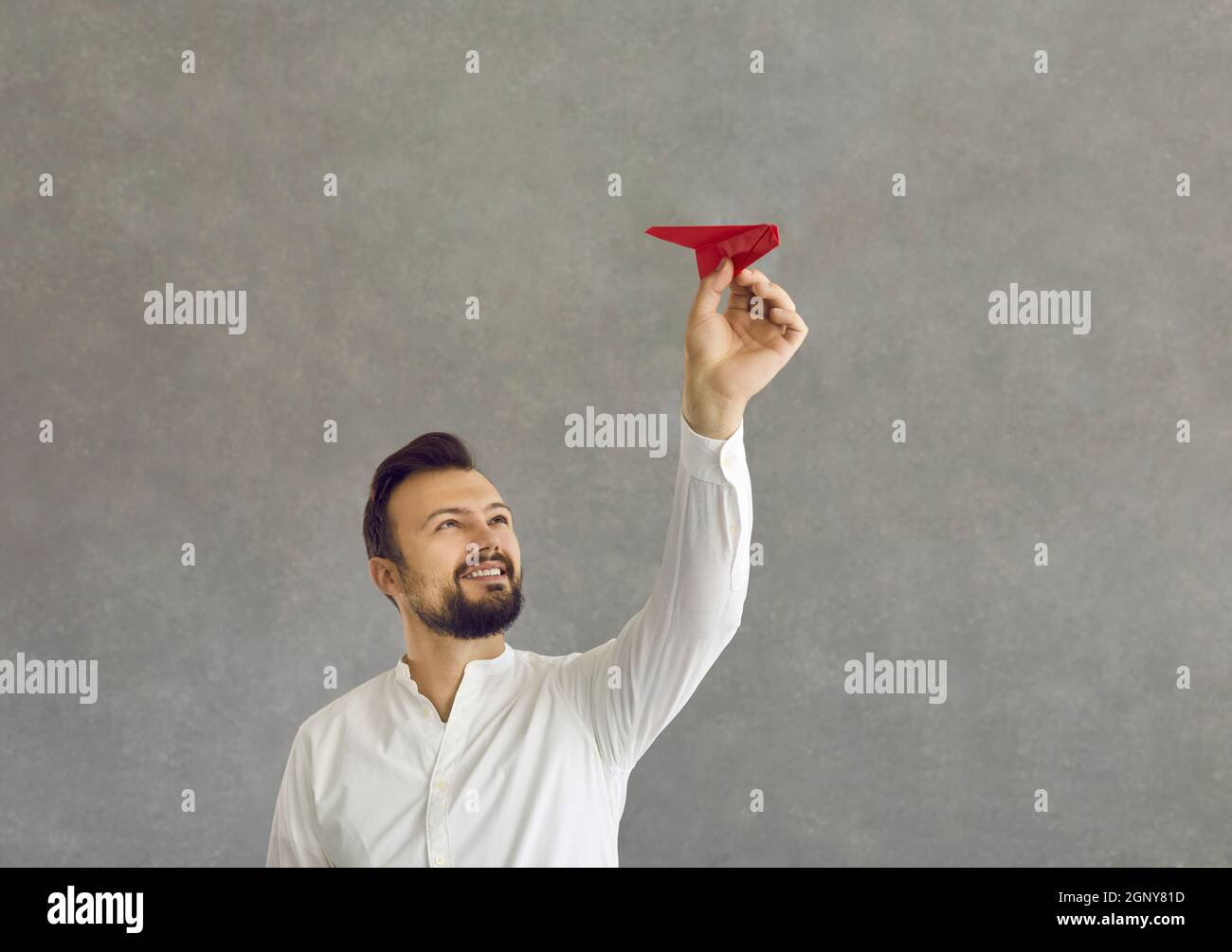 A happy young man throwing a paper aeroplane as a metaphor for aiming ...
