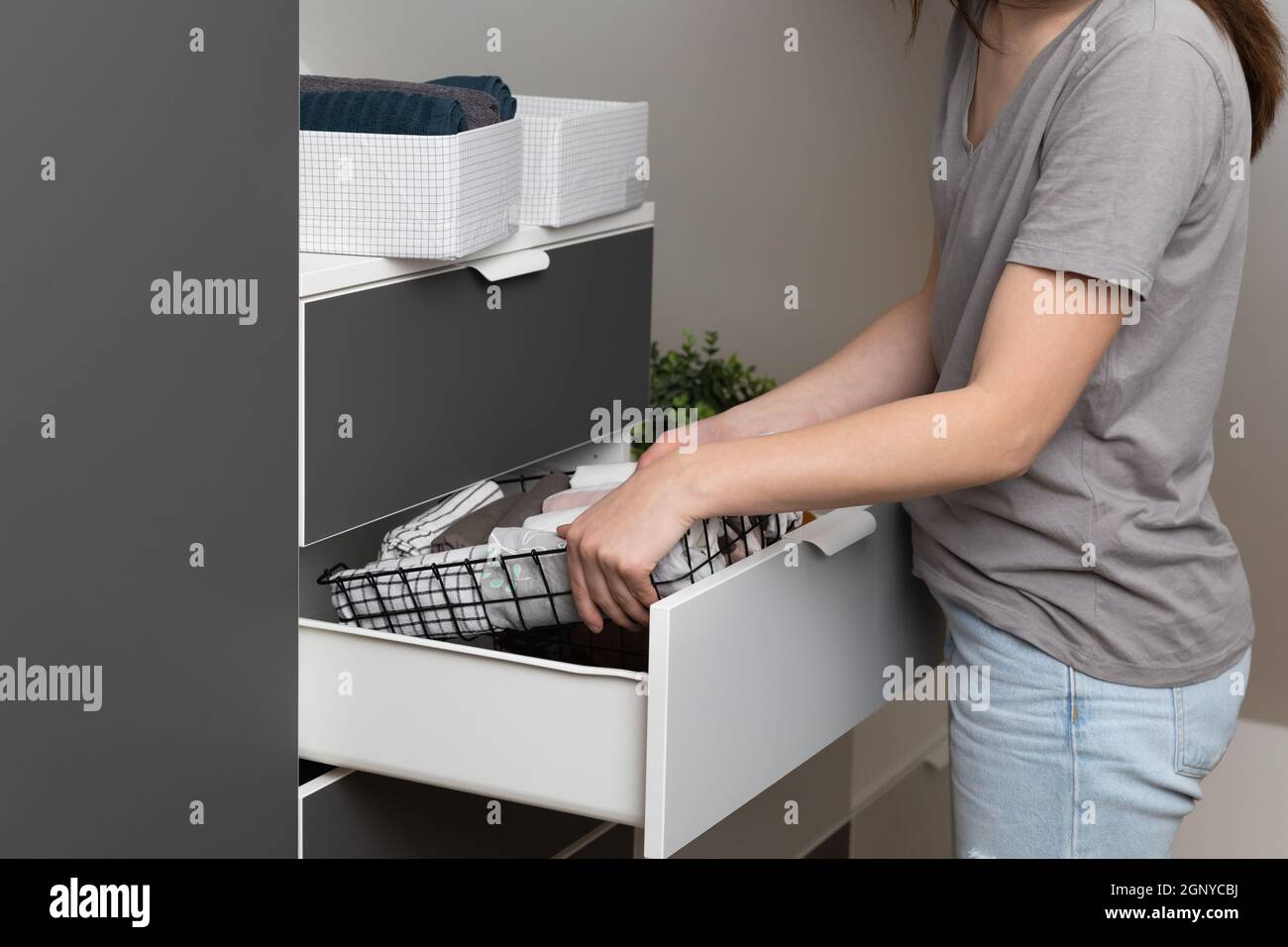 Vertical storage of clothing.Women organize clothes in a modern bedroom ...