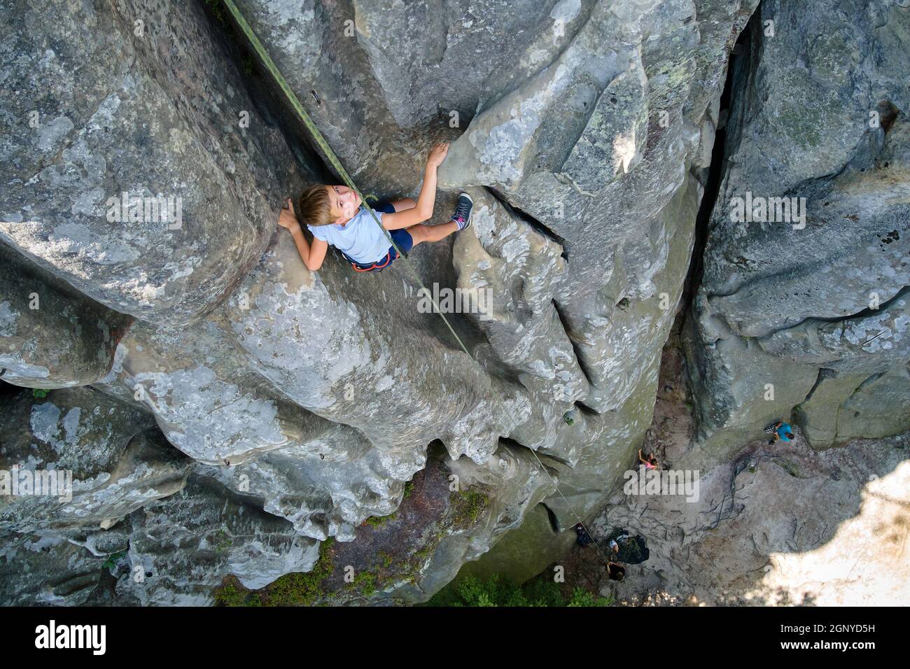Young child boy climbing steep wall of rocky mountain. Kid climber ...