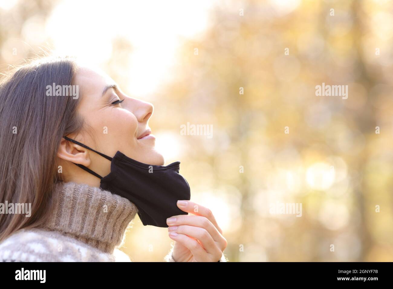 Side view portrait of a satisfied woman taking off mask breathing fresh ...