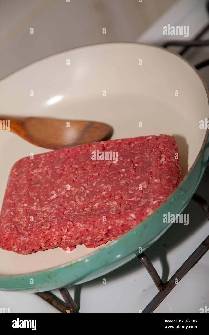 Raw ground beef in a frying pan with a wooden spoon Stock Photo - Alamy