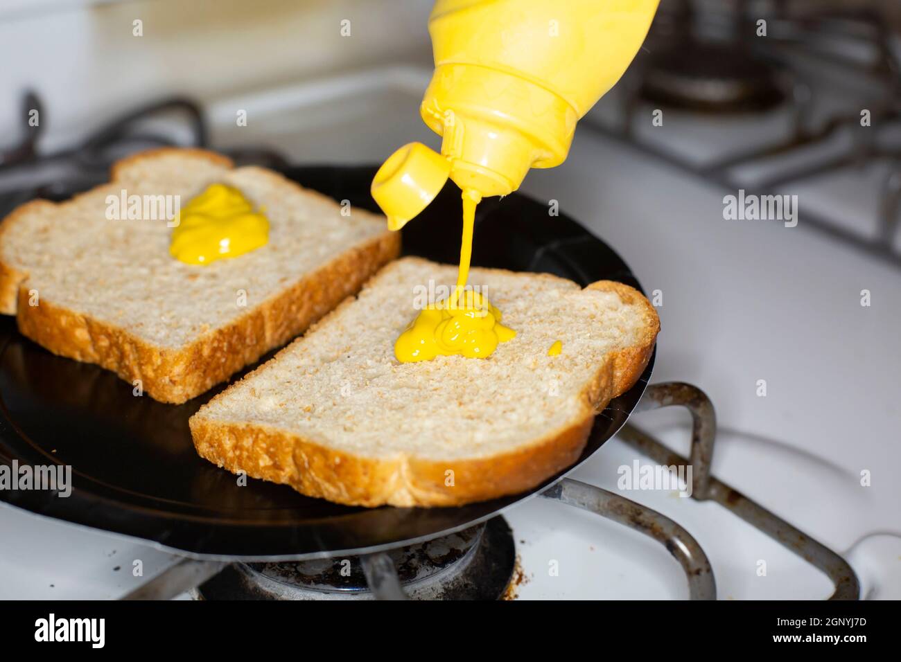 Pouring yellow mustard on two slices of bread Stock Photo - Alamy