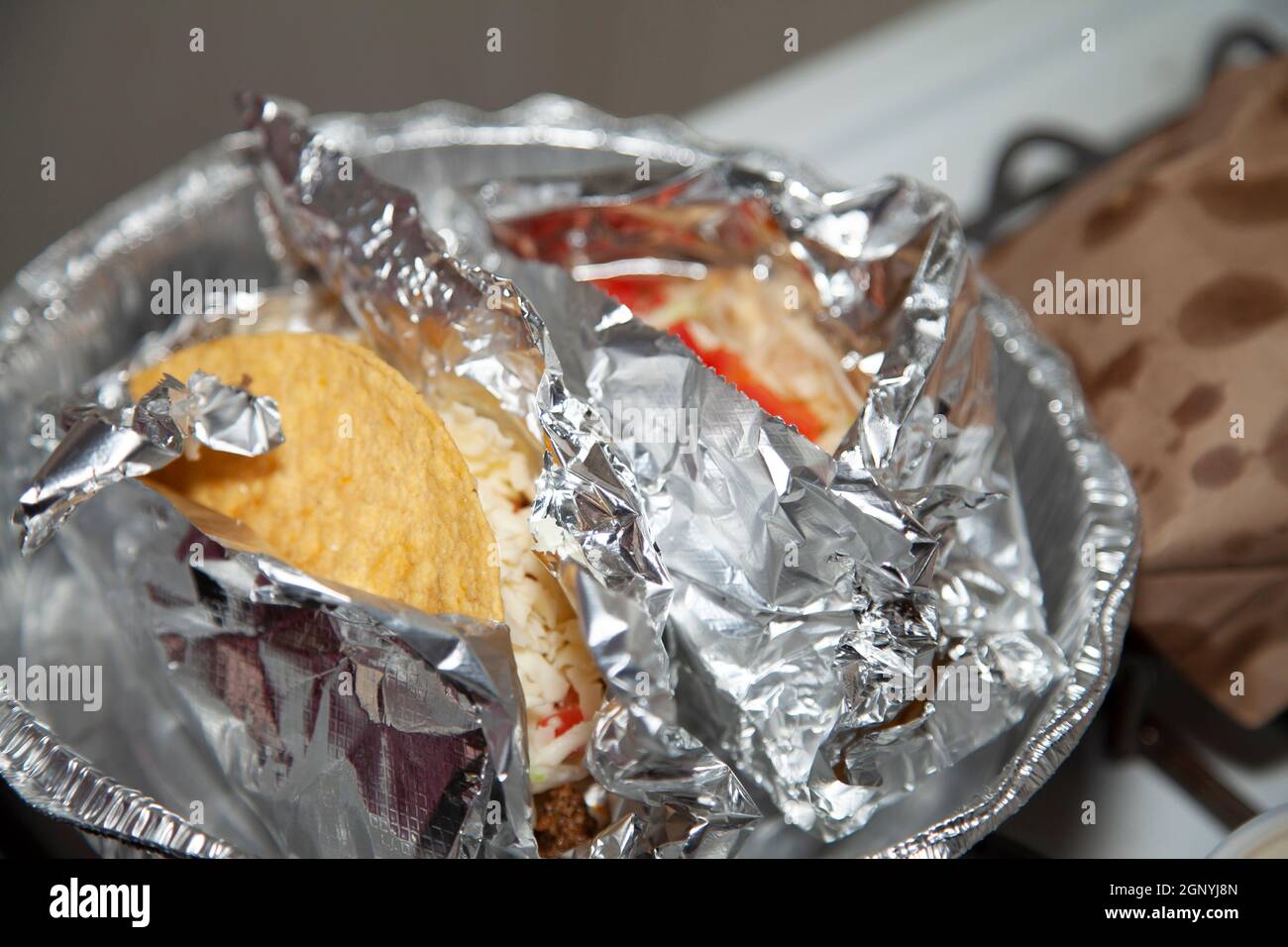 Pair of takeout tacos covered in white cheese and diced tomato Stock ...