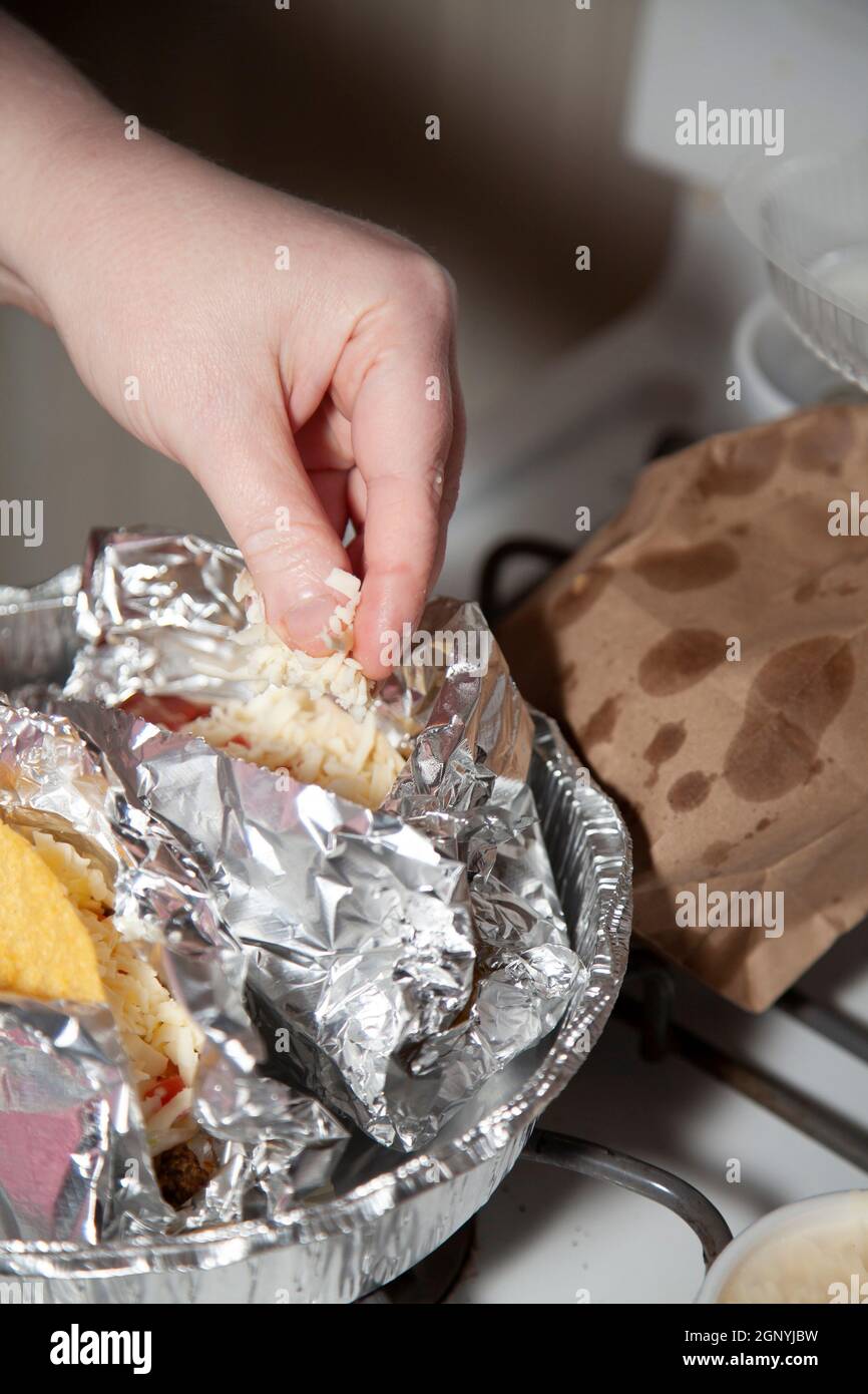 Woman dropping shredded white cheese on a pair of tacos Stock Photo - Alamy