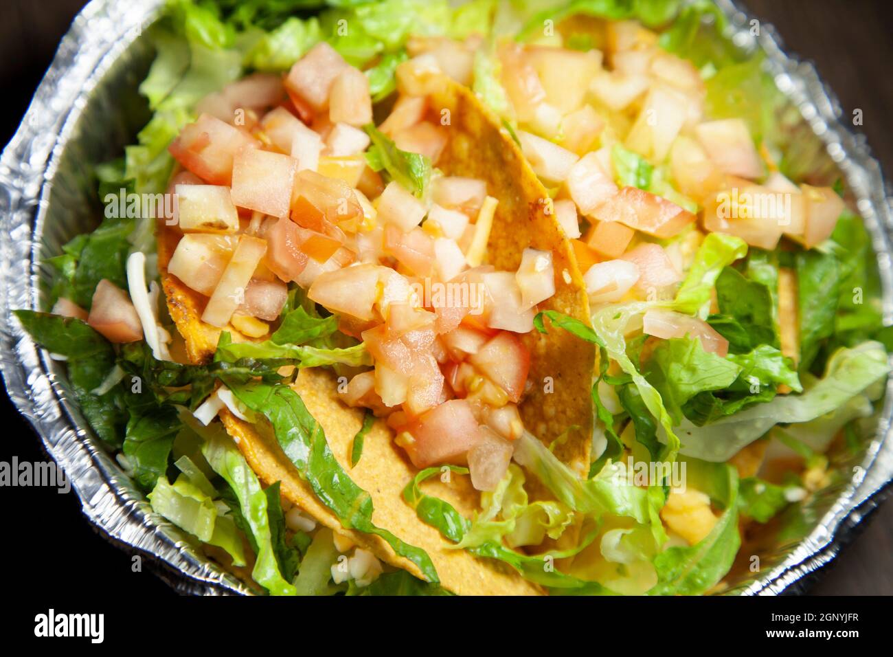 Tacos in a carry out tin with extra shredded lettuce and diced tomatoes ...