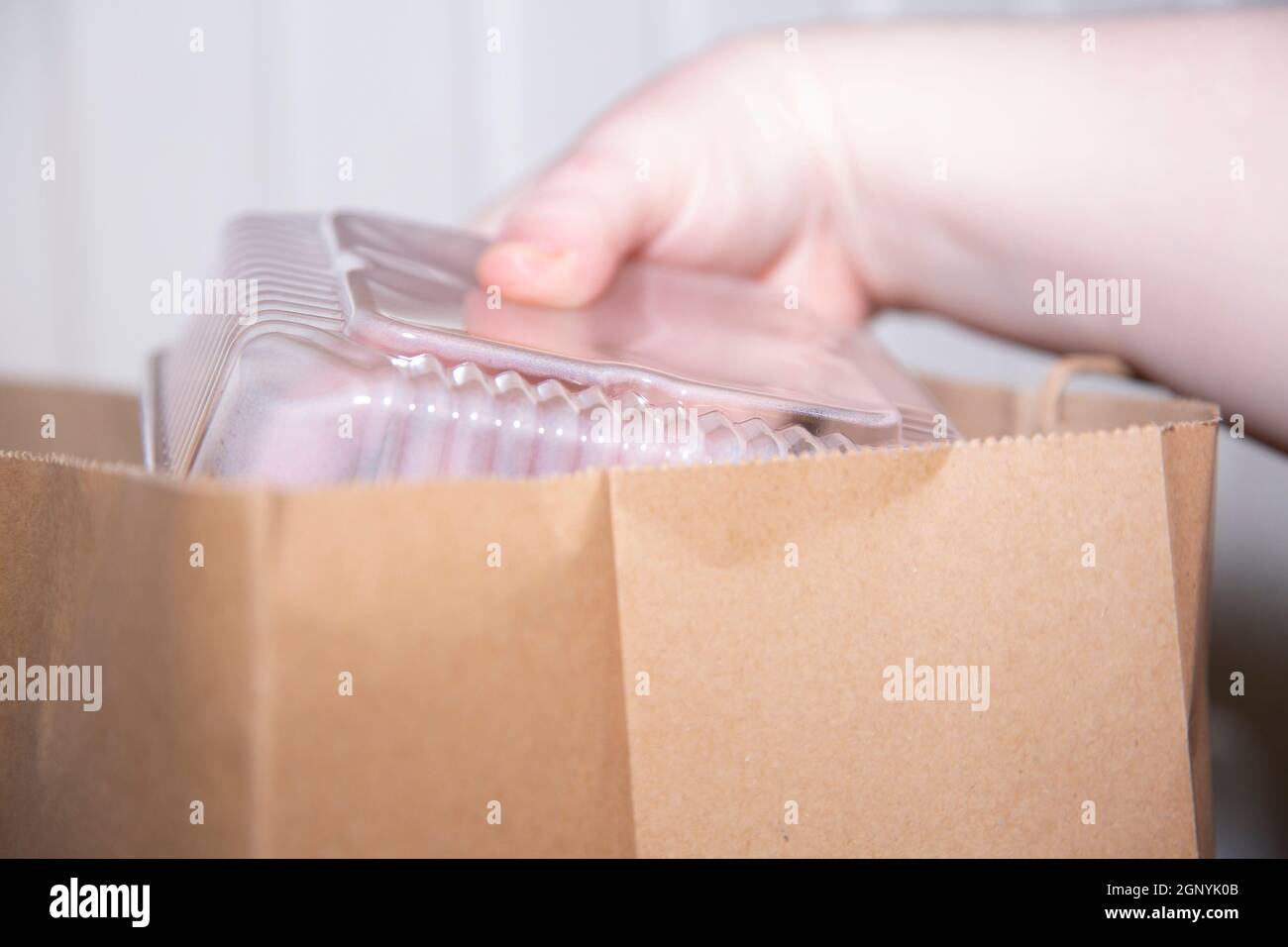 Woman pulling a fresh pastry box out of a grocery bag Stock Photo - Alamy