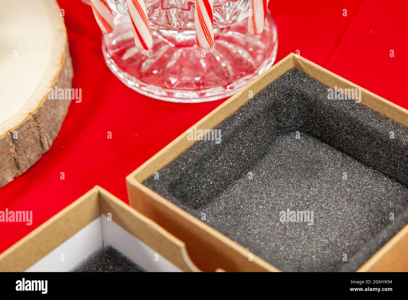 Empty, unwrapped gift box with candy canes in the background, on a red ...