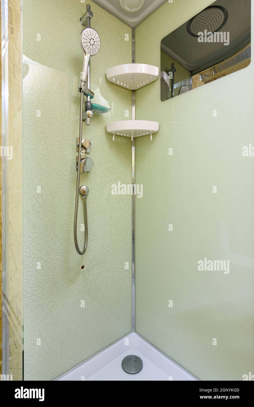 At the back wall of the shower stall on which the mixer and shower are ...
